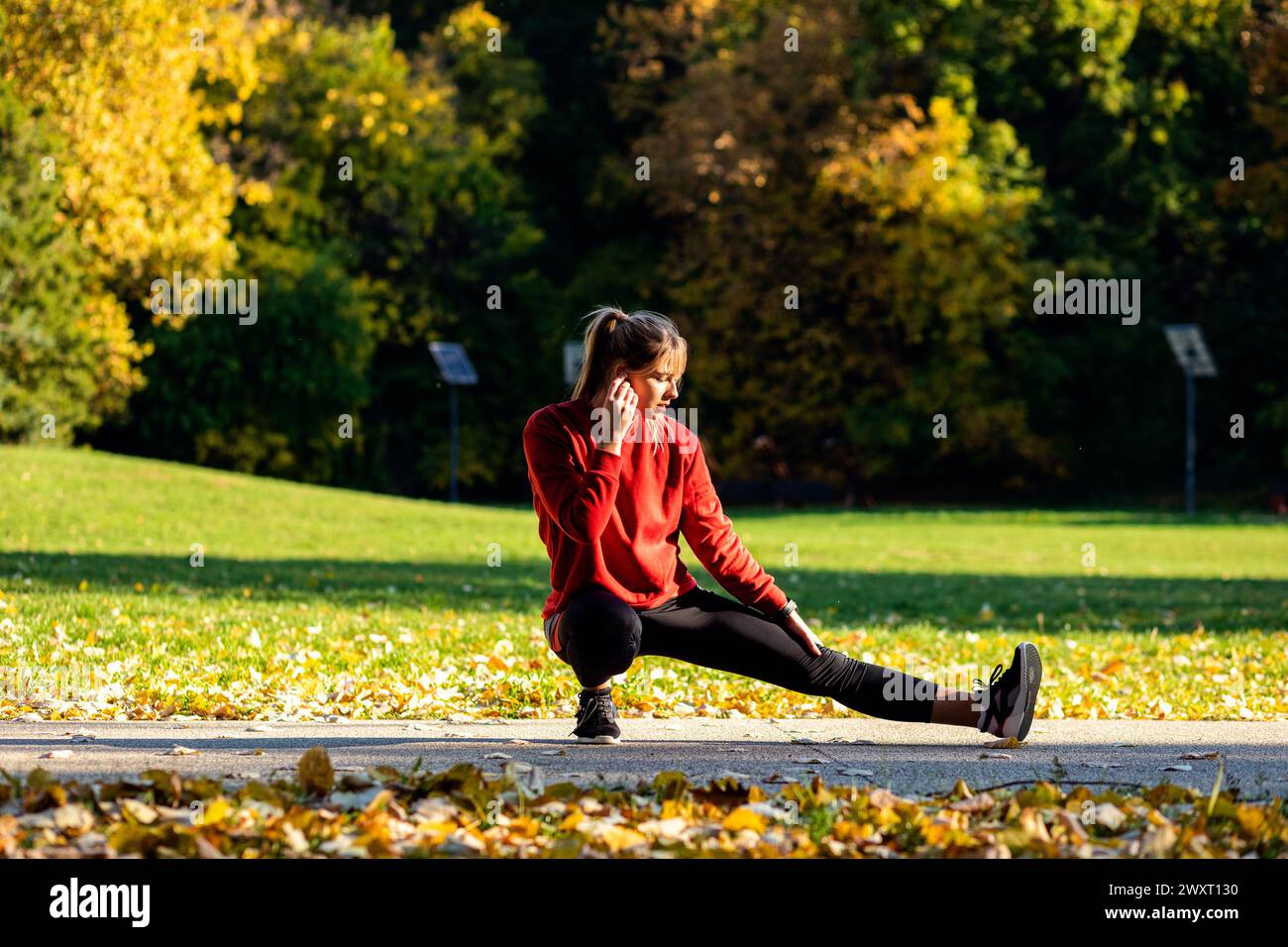 Young woman warming up and stretching before running in park Stock ...