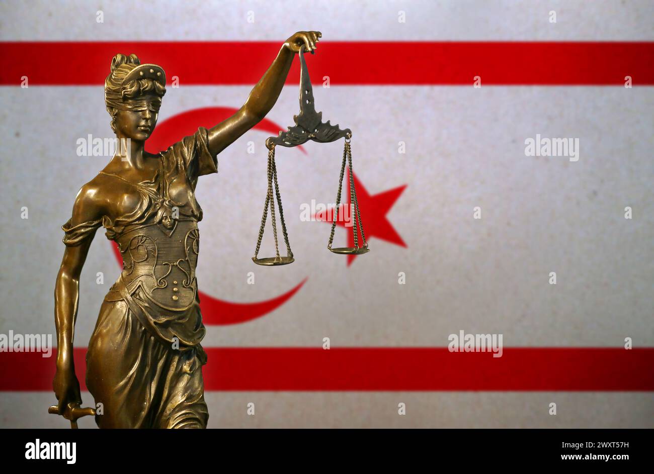 Close-up of a small bronze statuette of Lady Justice before a flag of ...