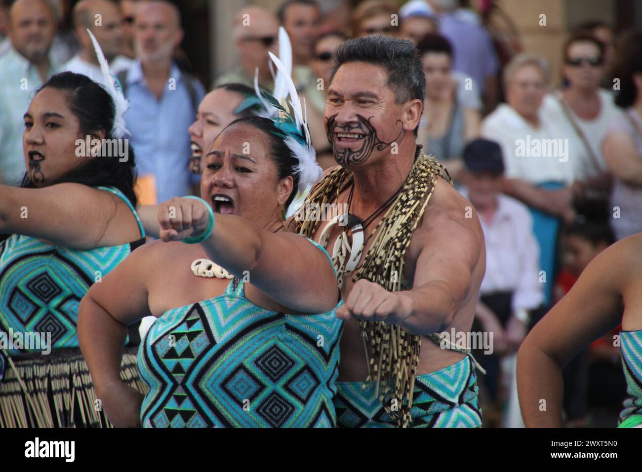 A group of men and women in tribal attire perform a traditional dance ...