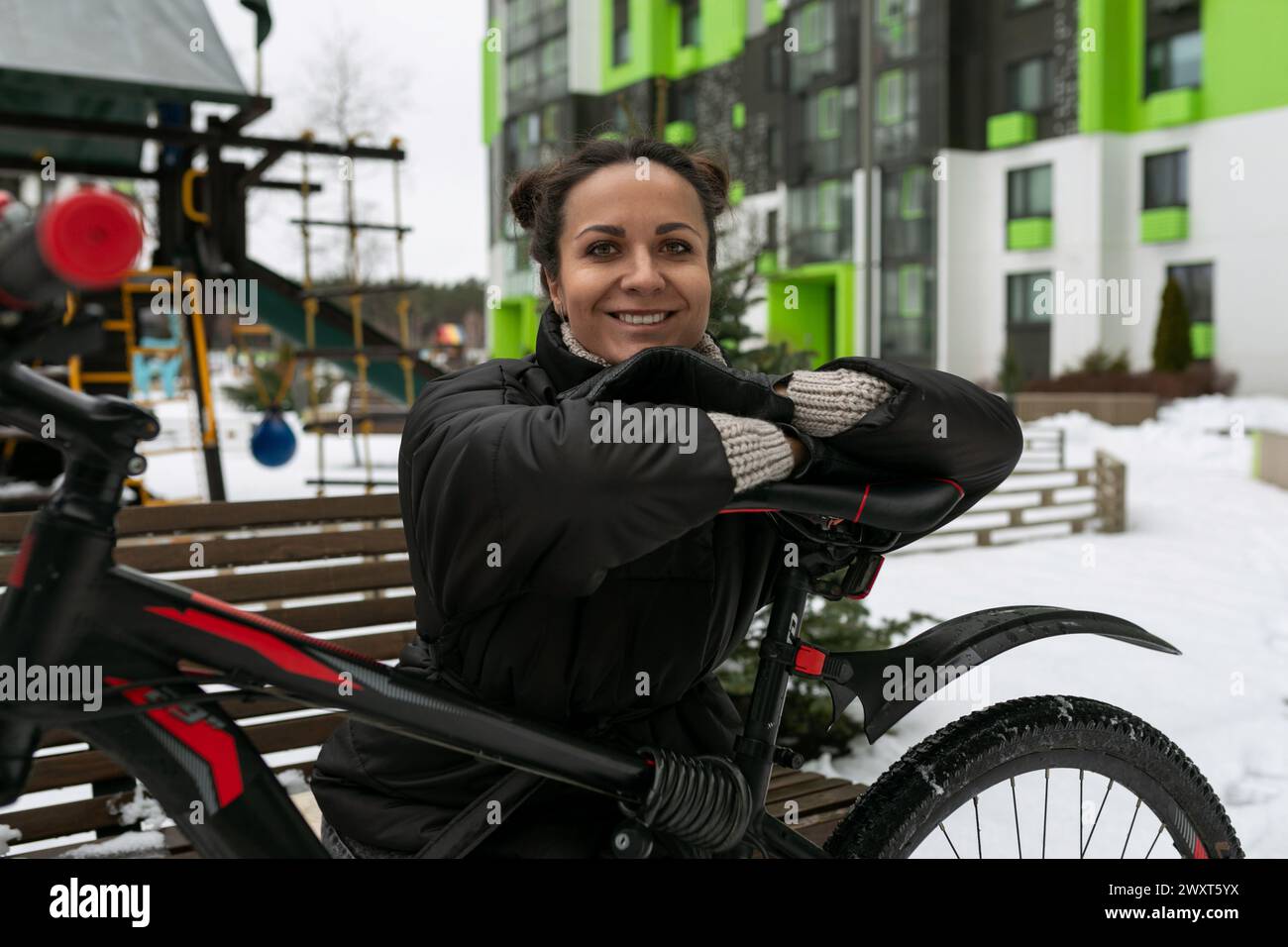 European young woman sat down on a bench to rest during a bike ride ...