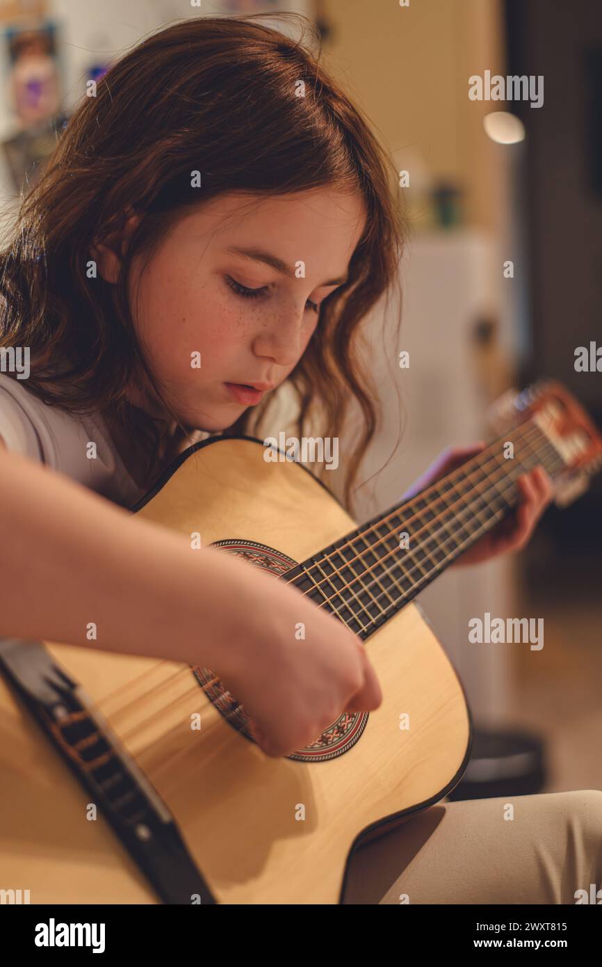Close up of a teenage girl learning to playing acoustic guitar at home ...