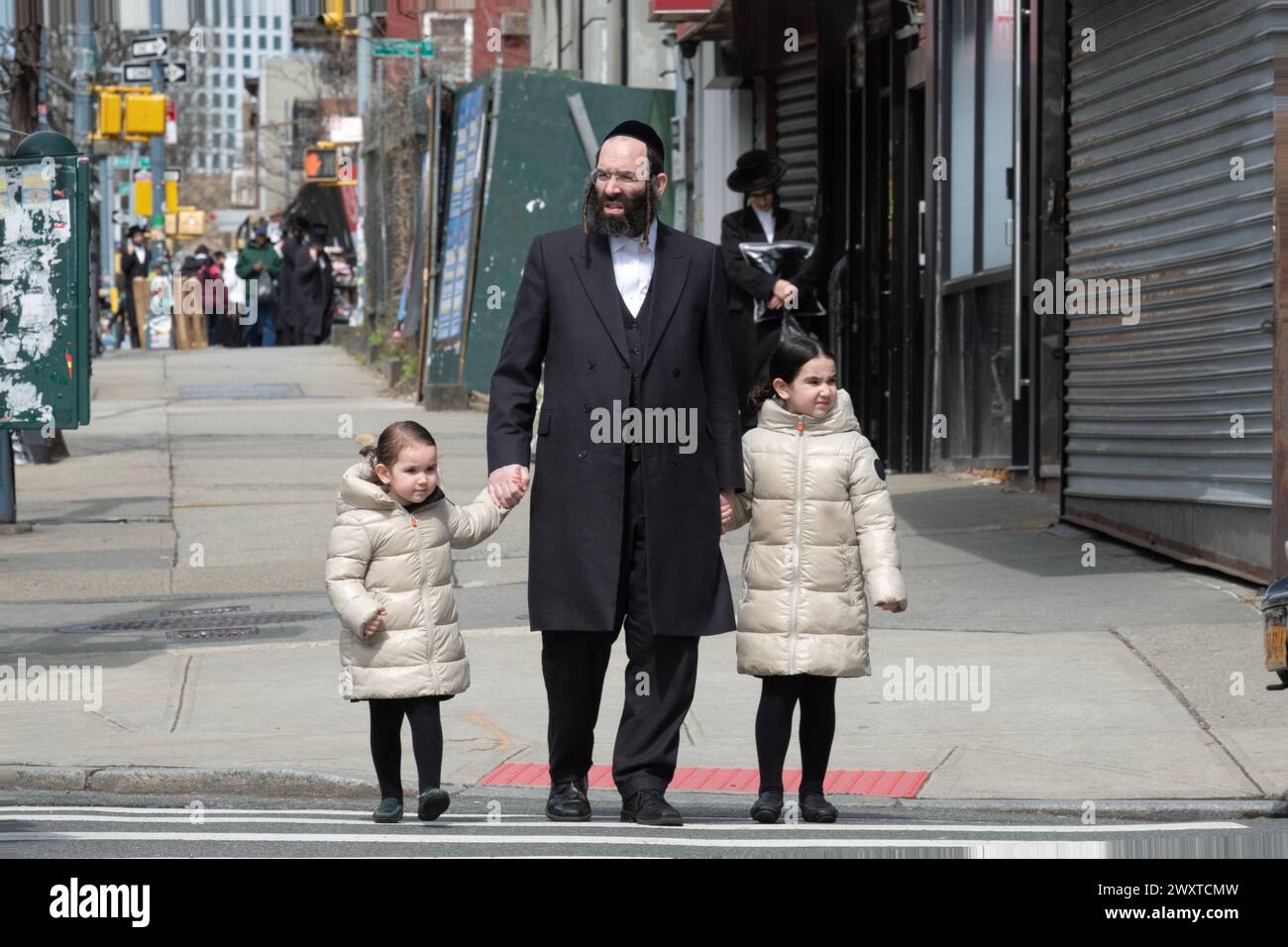 A Hasidic Jewish father and his identically dressed daughters cross a ...