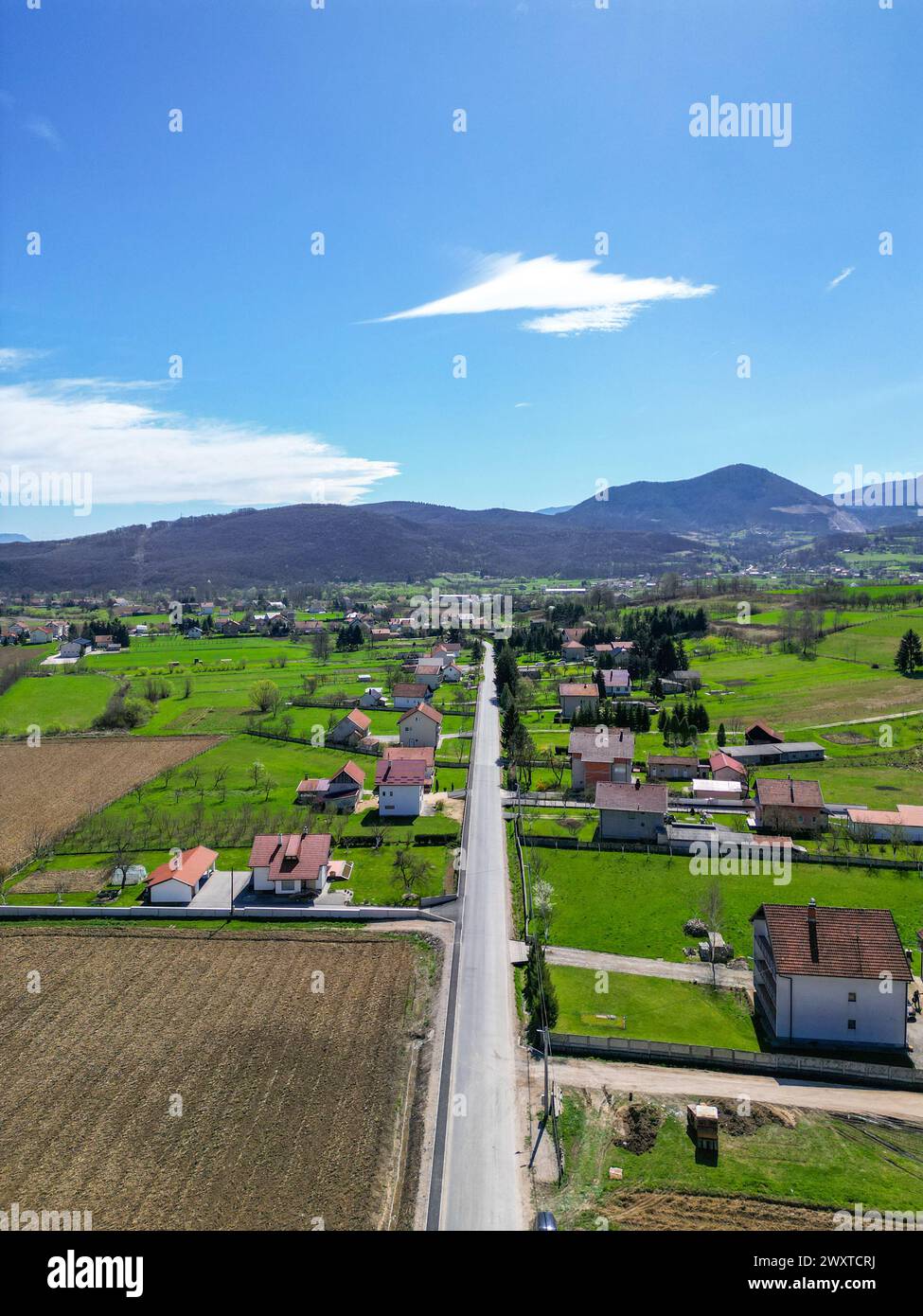 A rural landscape with road, farmland, and mountains in the background ...