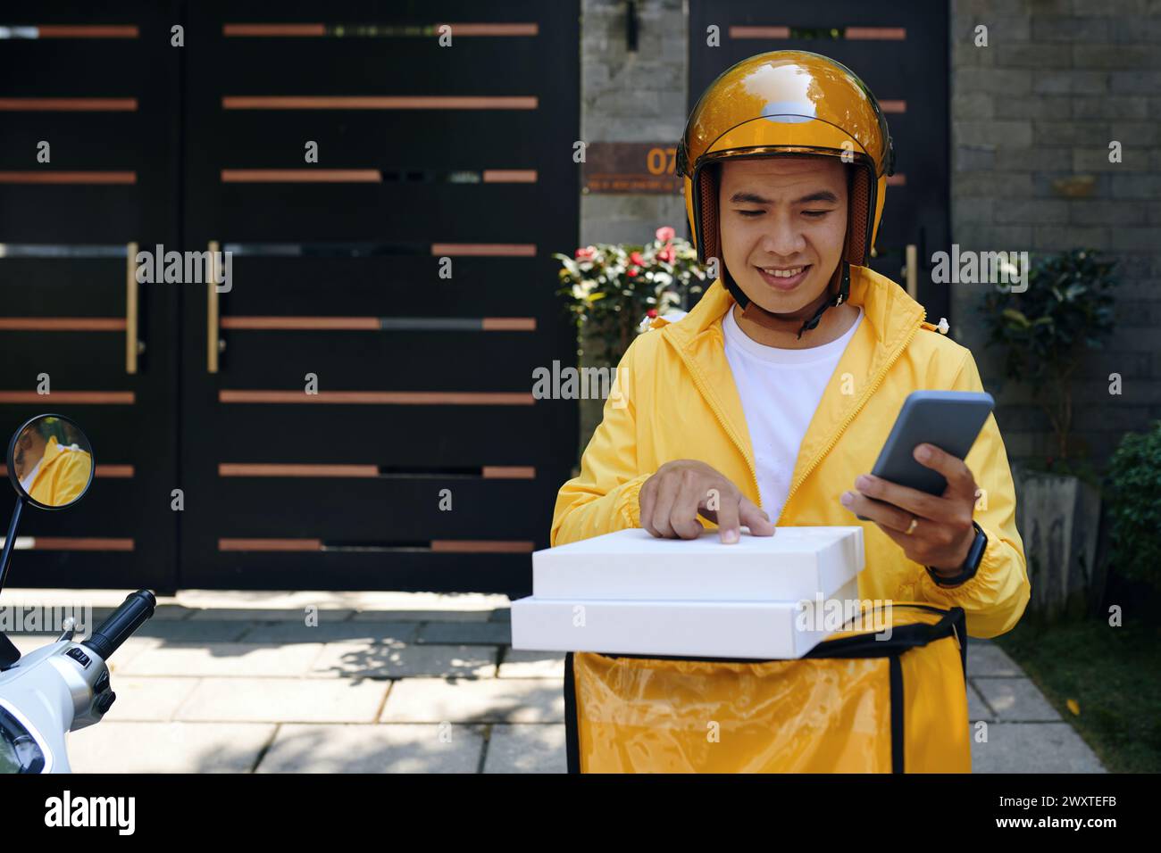 Courier checking address of customer on pizza box Stock Photo - Alamy