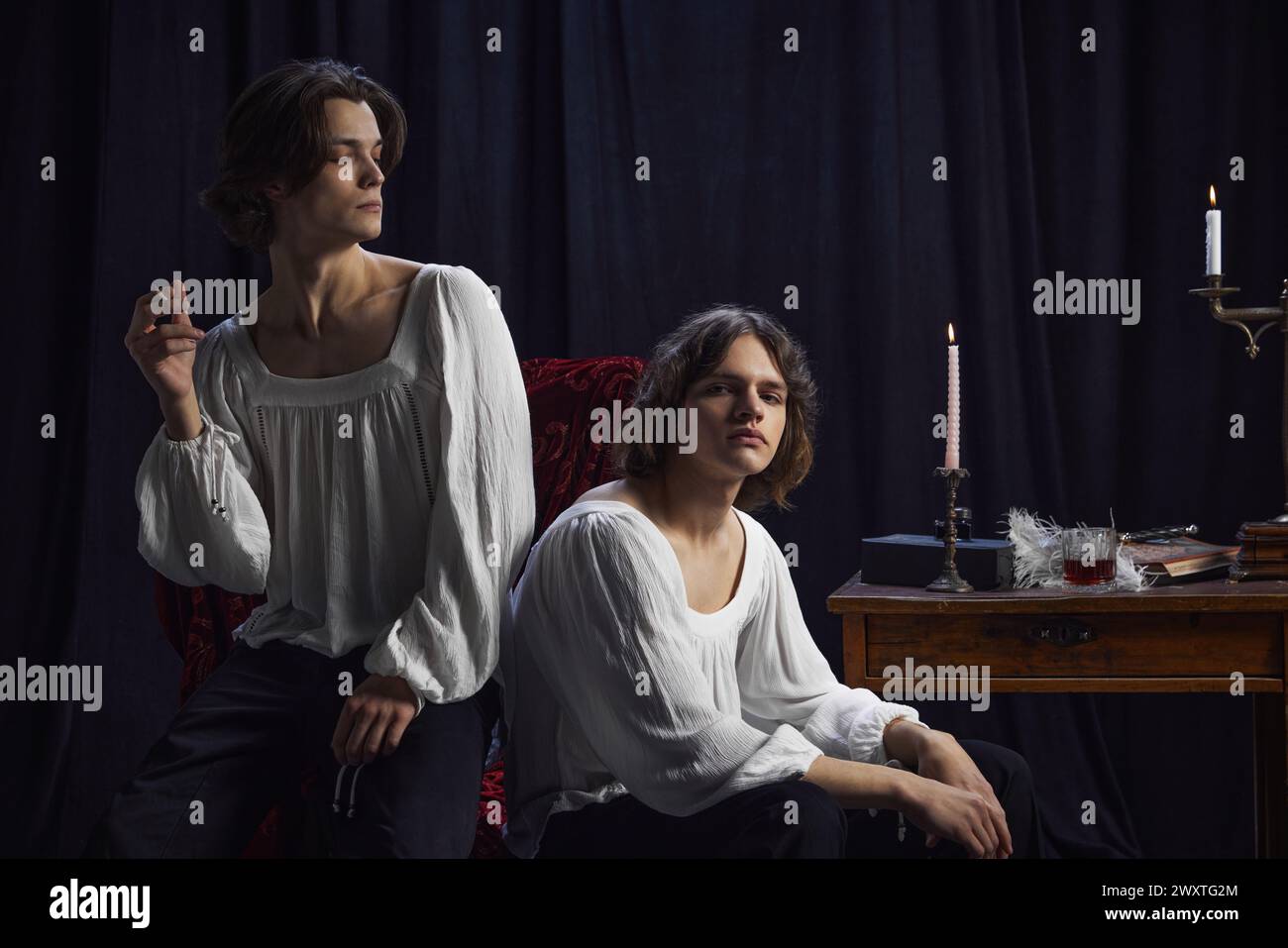 Portrait of two handsome men in white blouses sitting at room in ...