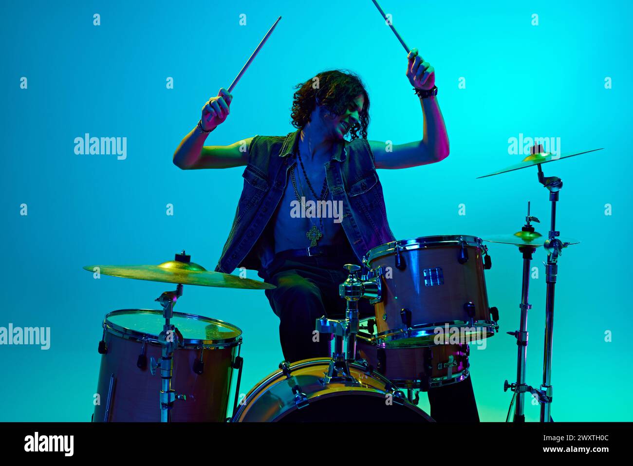 Enthusiastic young boy, drummer with curly hair playing drums against ...
