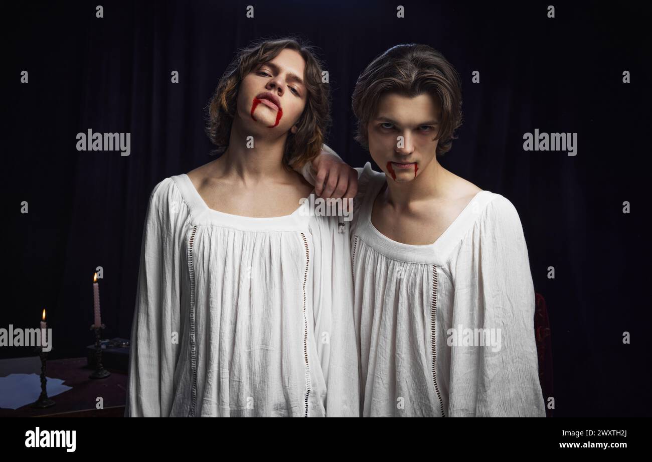 Two handsome man looks as vampires in old-fashion clothes looking at ...