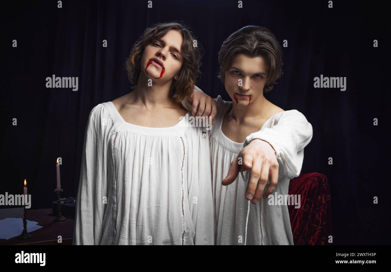 Two handsome man looks as vampires in historical clothes and looking at ...
