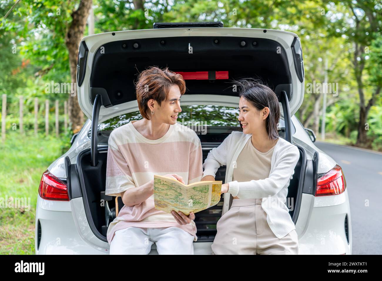 Young couple reading maps in car trunk Stock Photo - Alamy