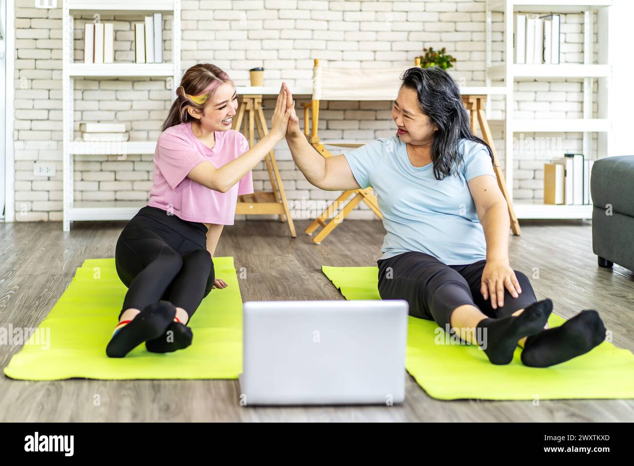 The daughter and her mother high-fiving each other while working out on ...