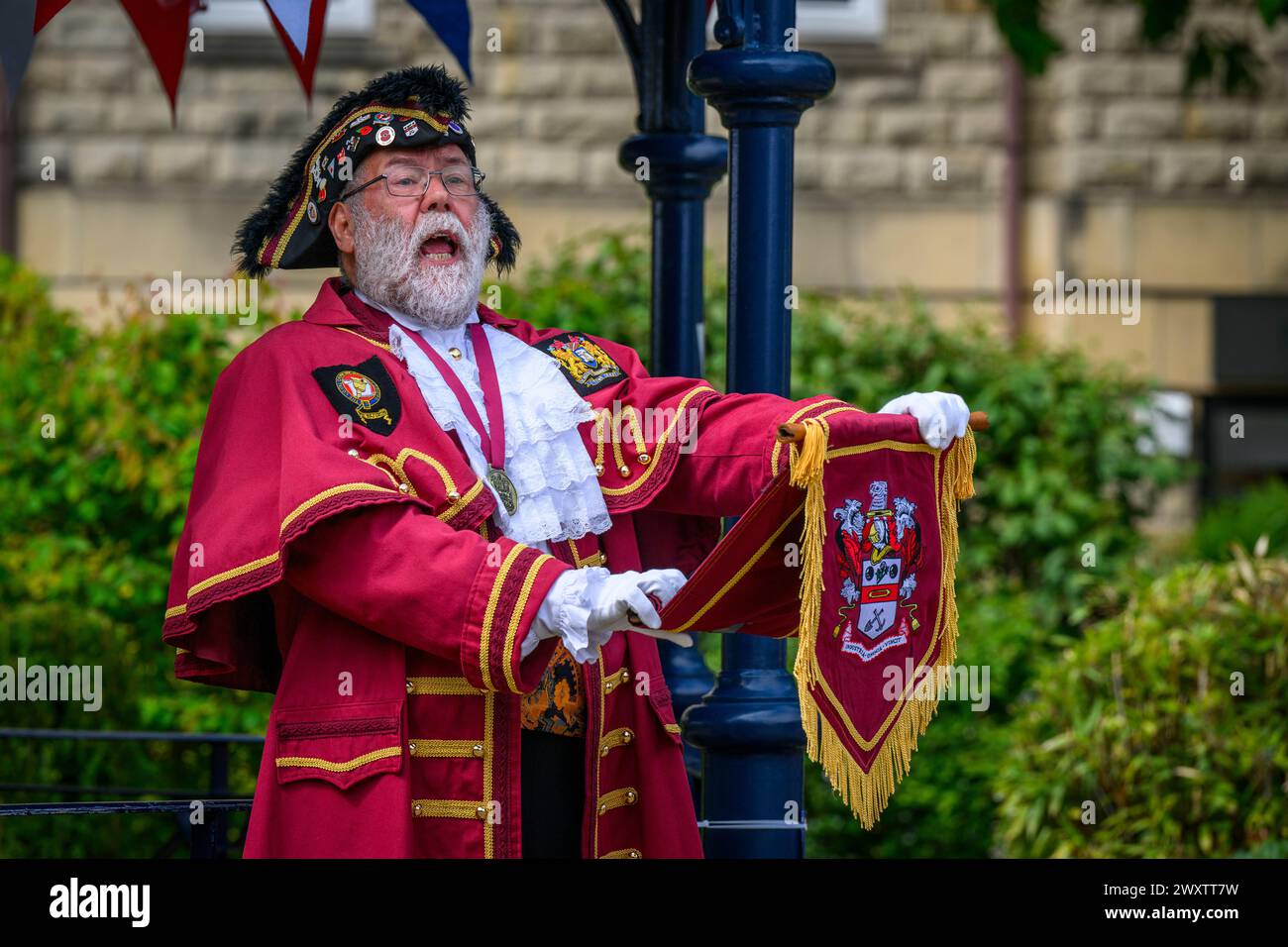 Male town crier (colourful braided crier's uniform) proclaiming, making ...