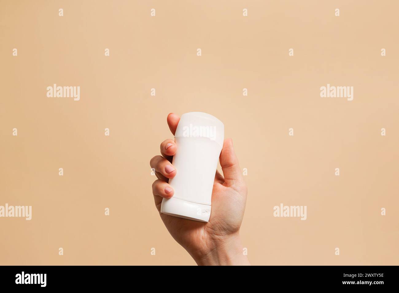 Hand holding antiperspirant, white deodorant on beige background, copy ...