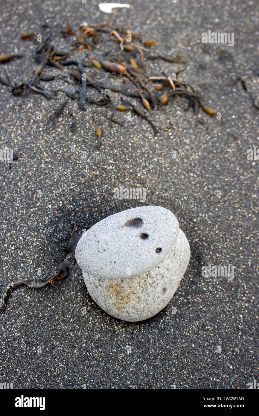 Two bigger pebbles one on the other. Three holes - dots on the top one ...