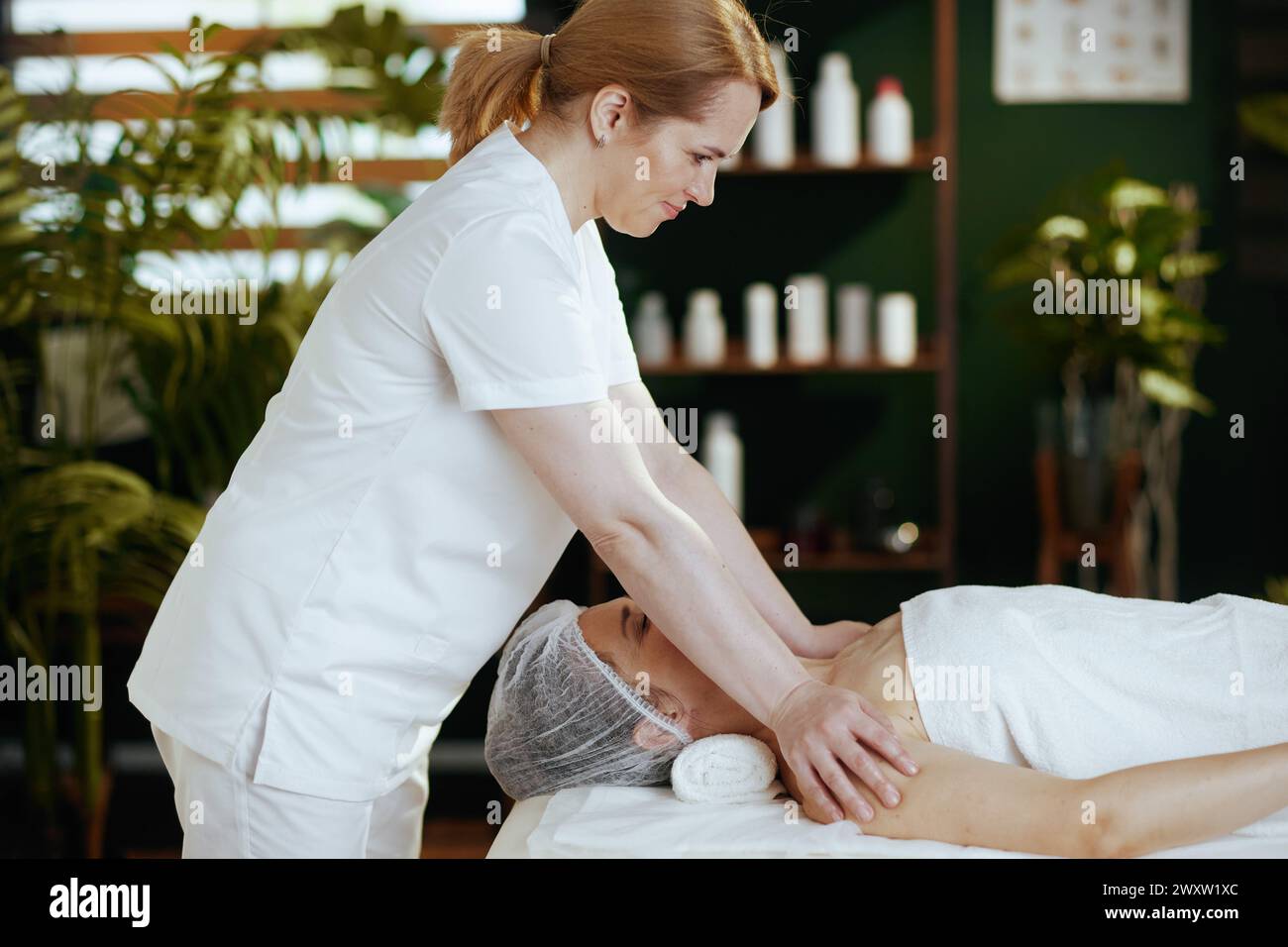 Healthcare time. massage therapist in spa salon massaging clients shoulder on massage table ...