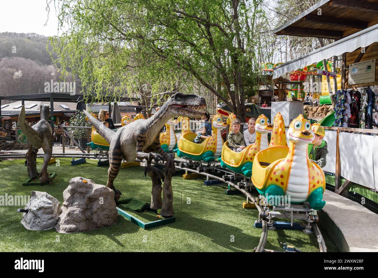 Children on a dinosaur roller coaster outdoor in an amusement park in ...