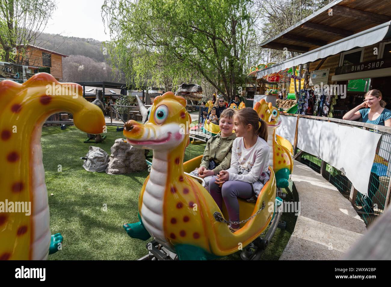Children on a dinosaur roller coaster outdoor in an amusement park in ...