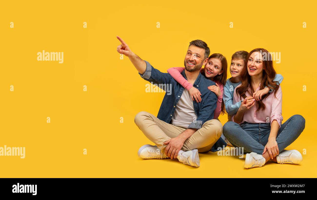 Happy family sitting together and pointing up Stock Photo - Alamy