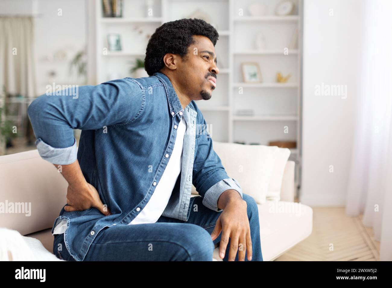 Black Man Experiencing Lower Back Pain at Home Stock Photo - Alamy