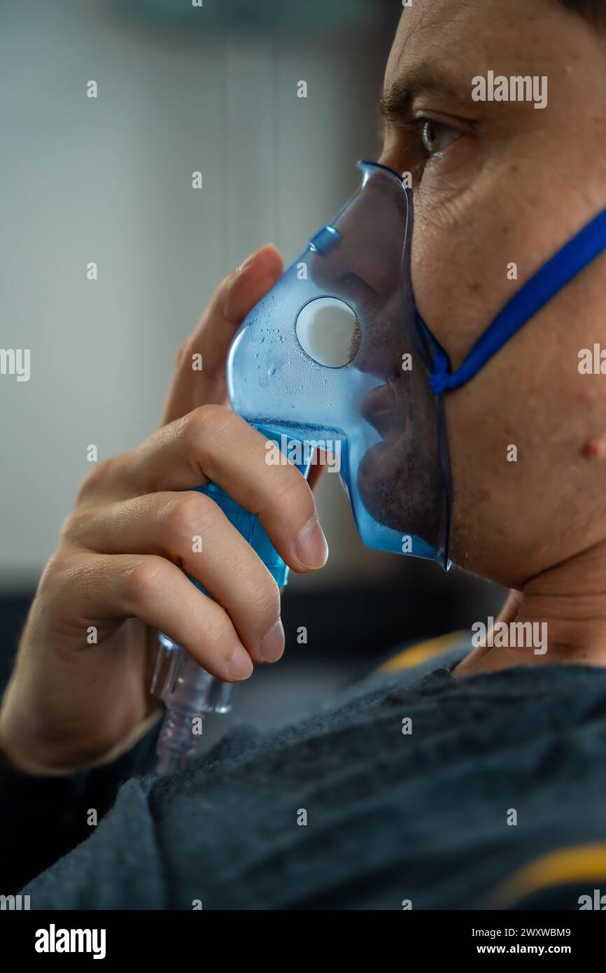 Unhealthy man wearing nebulizer mask in home. Health, medical equipment ...