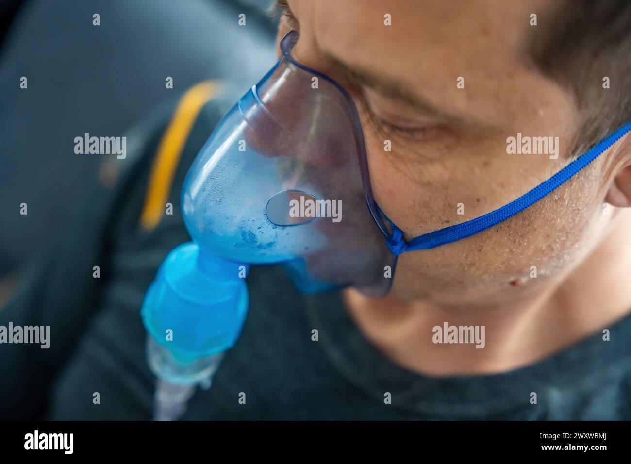 Close up view of unhealthy man wearing nebulizer mask in home. Health ...
