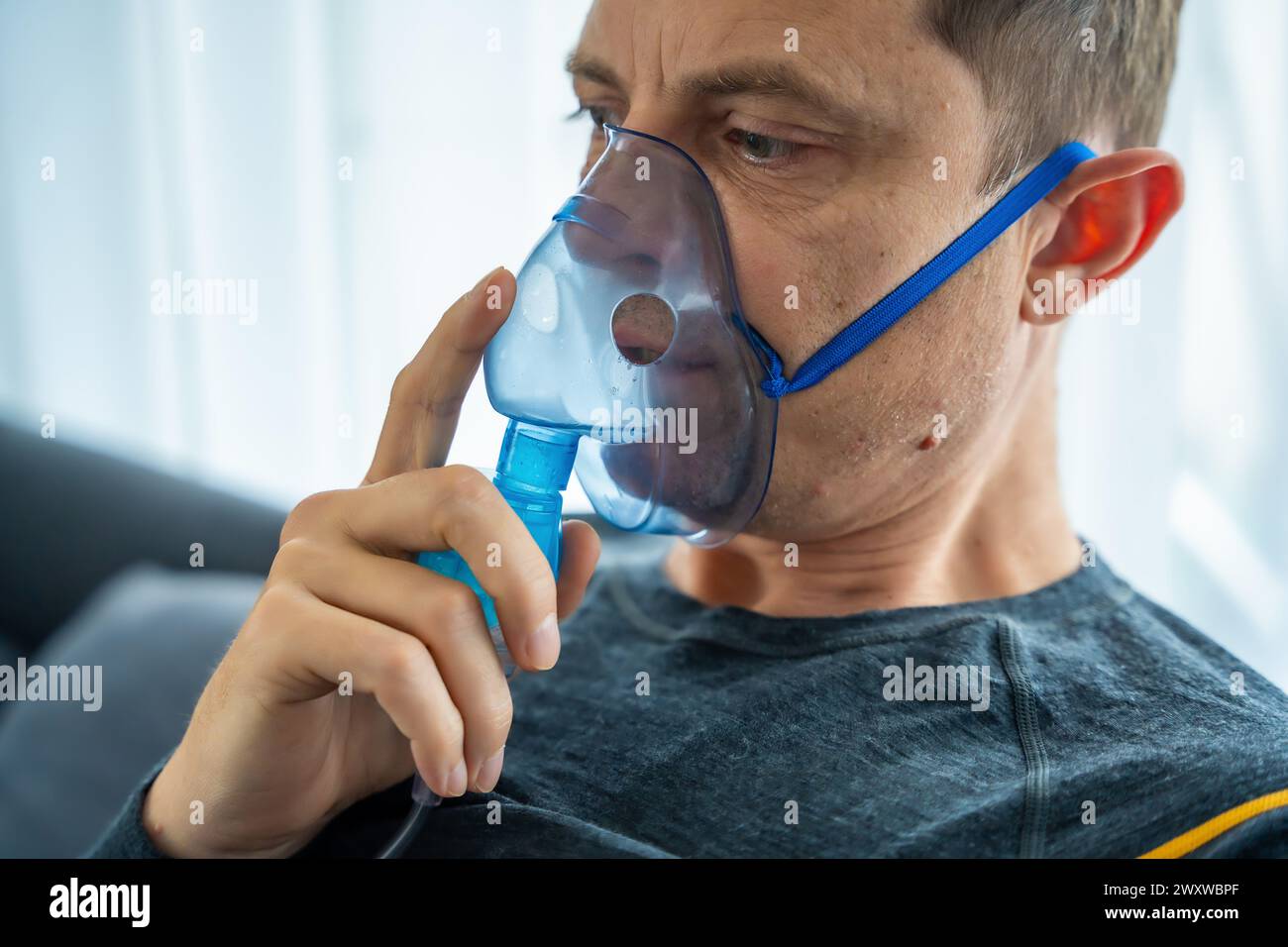 Unhealthy man wearing nebulizer mask in home. Health, medical equipment ...
