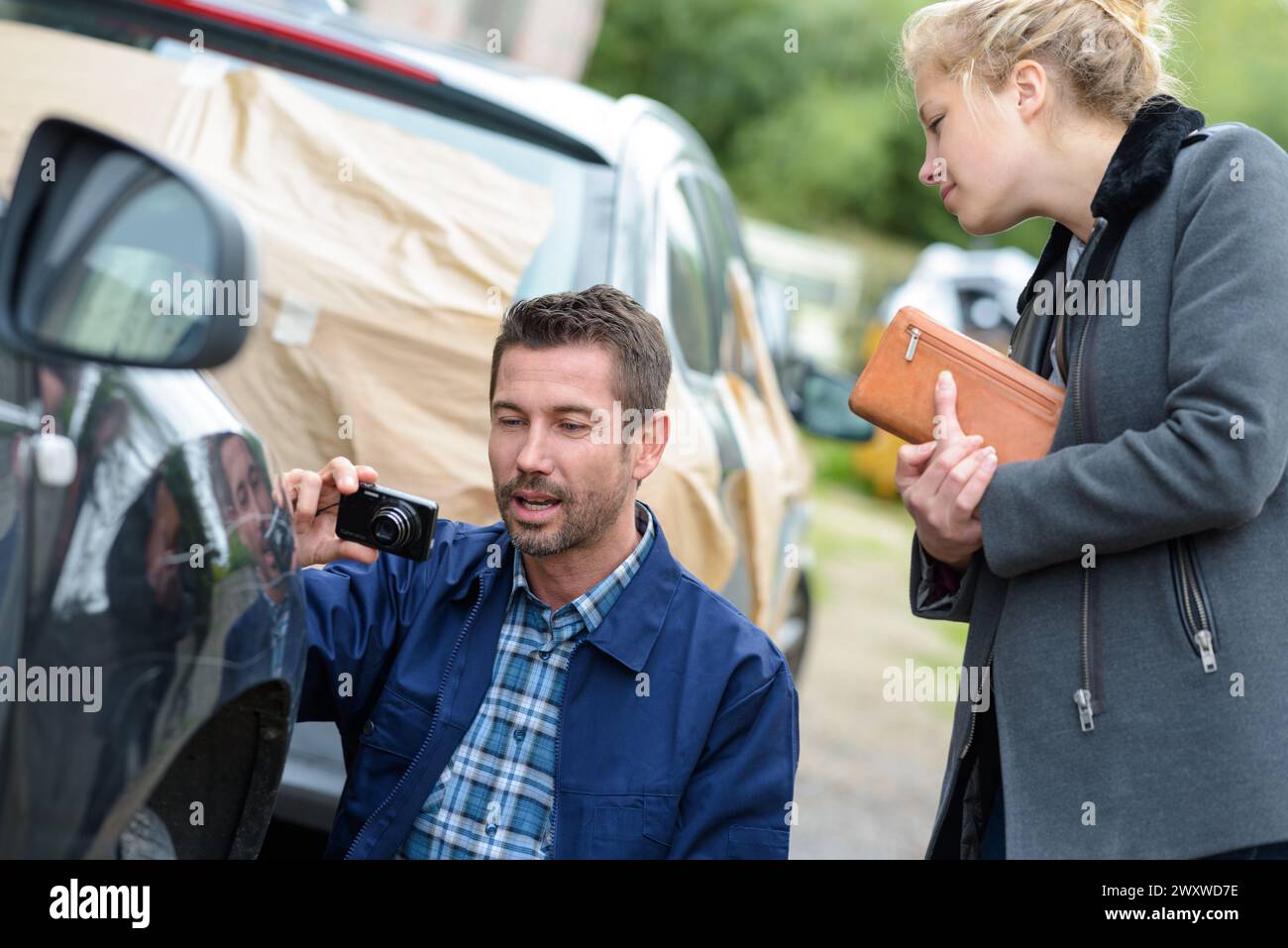loss adjuster taking photograph of damage to car Stock Photo - Alamy