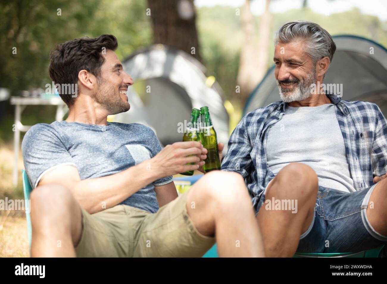 male friends sitting on chairs talking drinking beer Stock Photo - Alamy