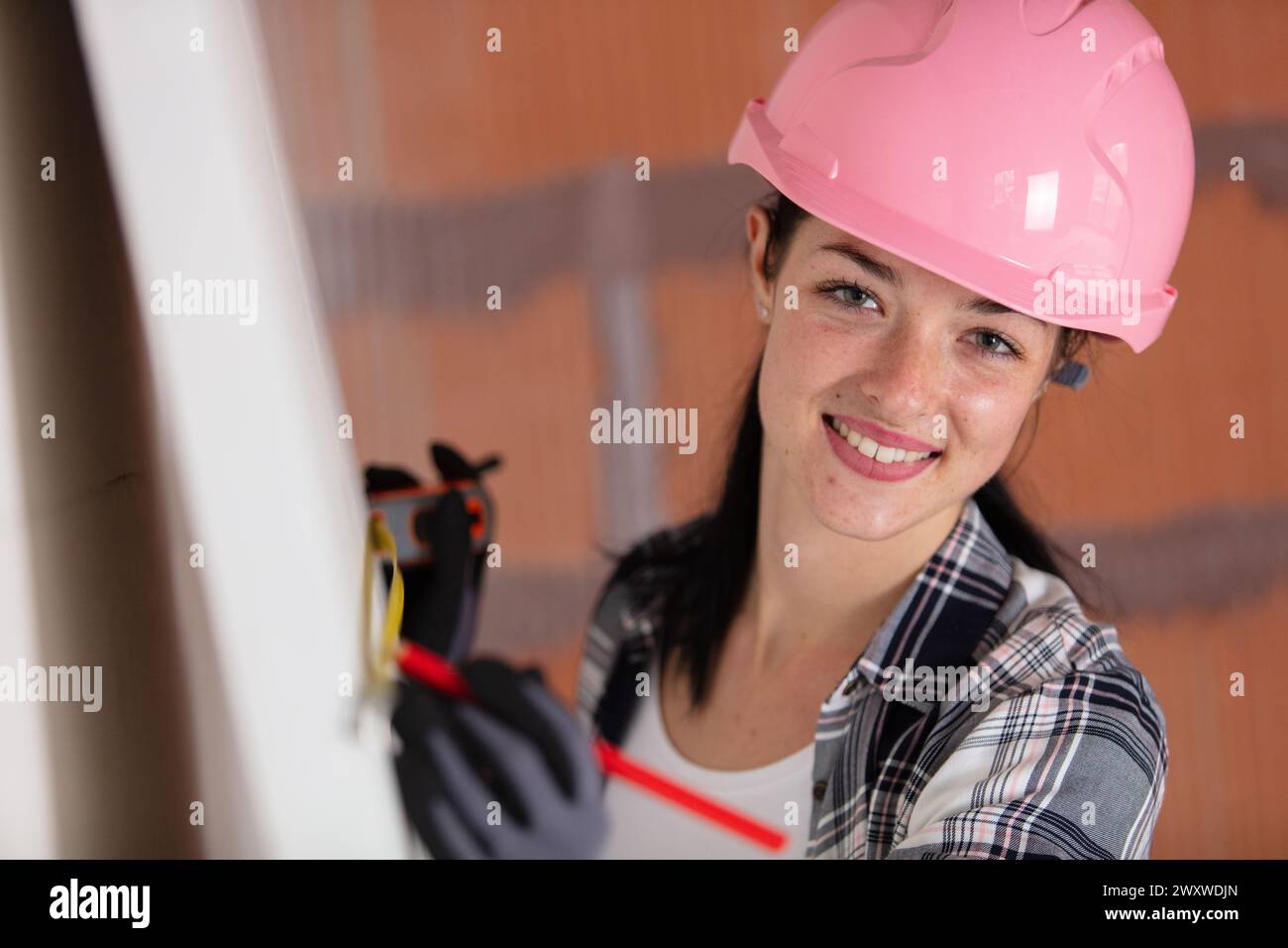 young female construction worker marking the wall with pencil Stock ...