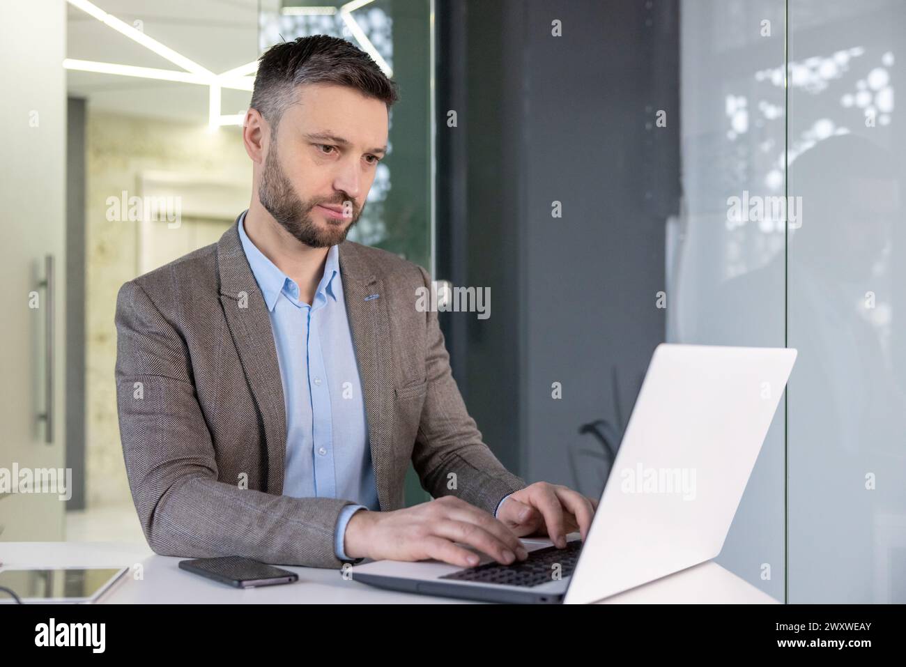 Focused mature male professional using computer in a contemporary ...