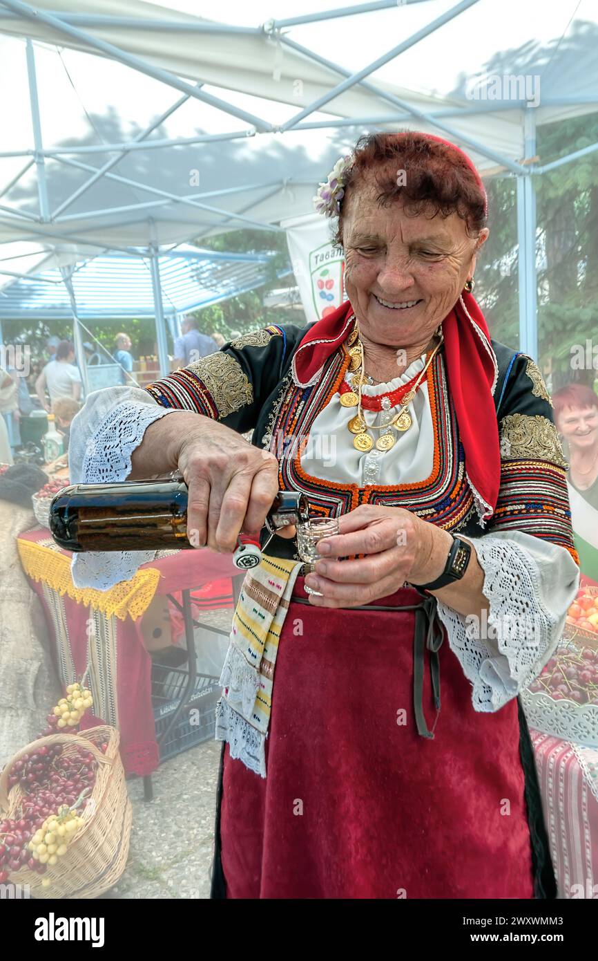 A woman offers a home-made fruit spirit. "Rakija". Cherry Feast ...