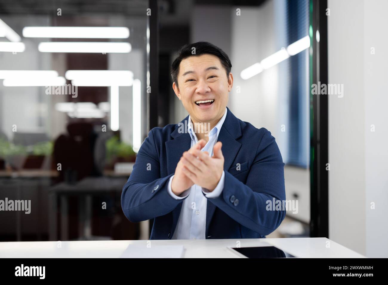 Enthusiastic mature businessman clapping hands with joy at his office ...