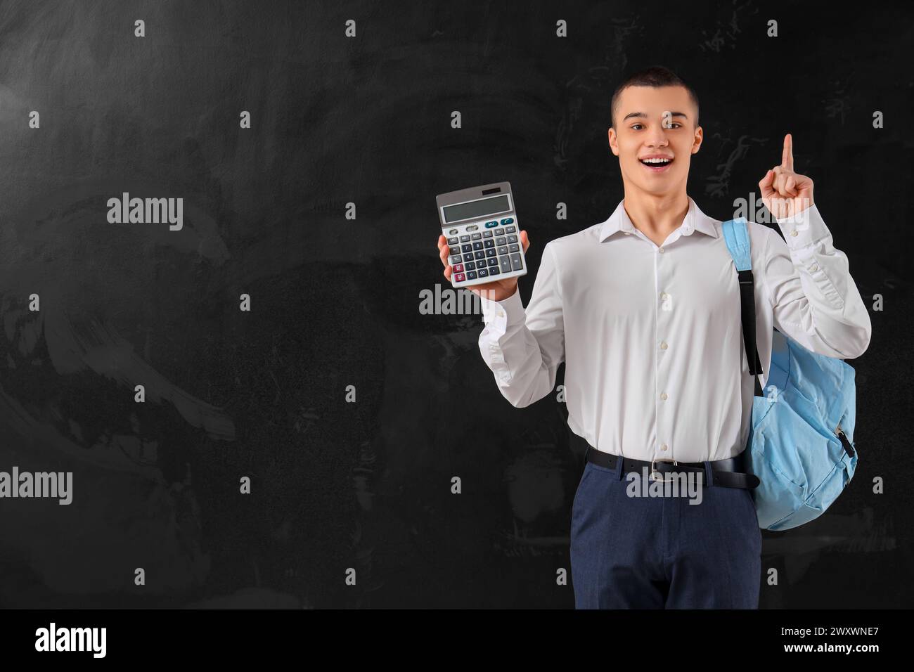 Male student with calculator pointing up on blackboard background. End ...