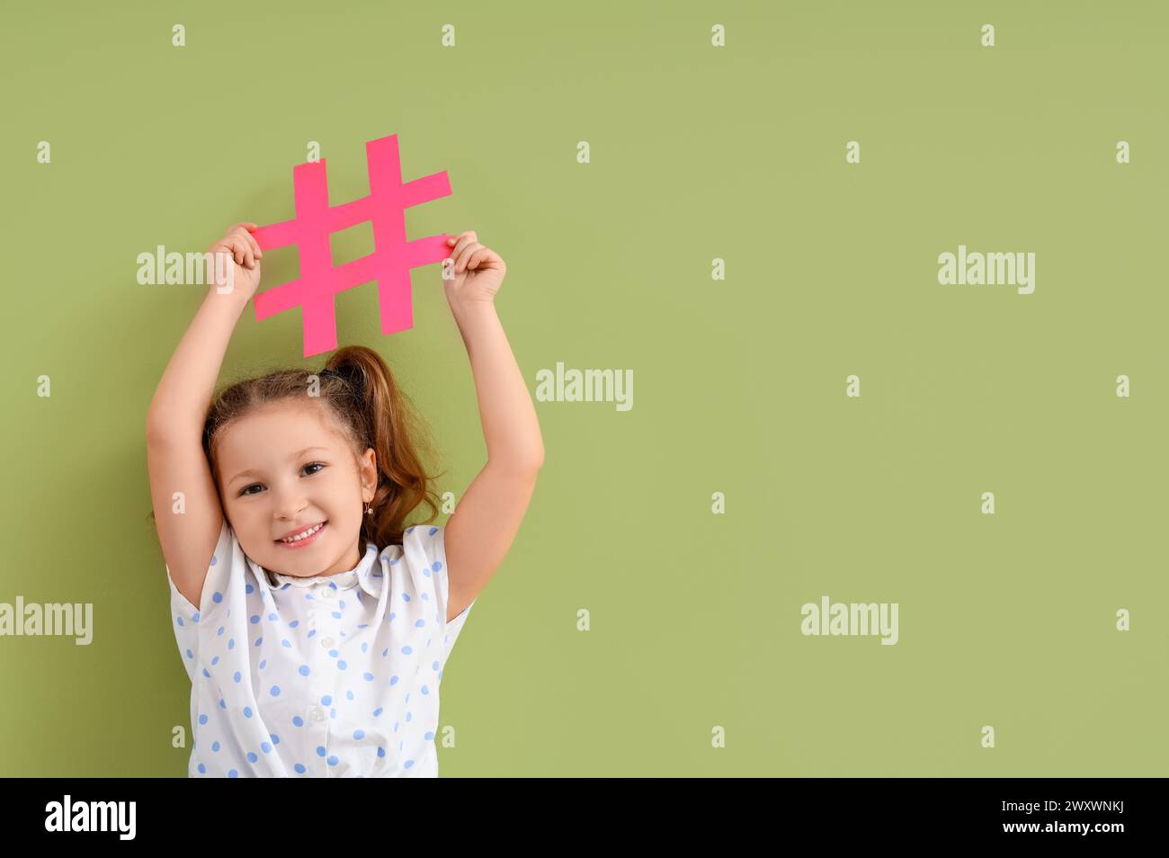 Cute little girl with hashtag on green background Stock Photo - Alamy