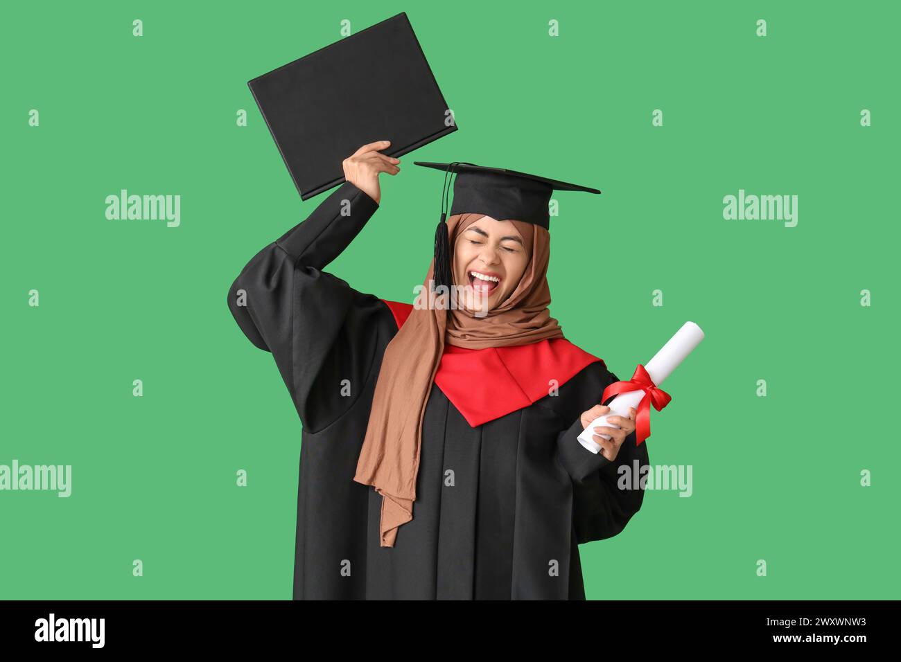 Muslim female graduate student with diploma throwing mortar board up on ...
