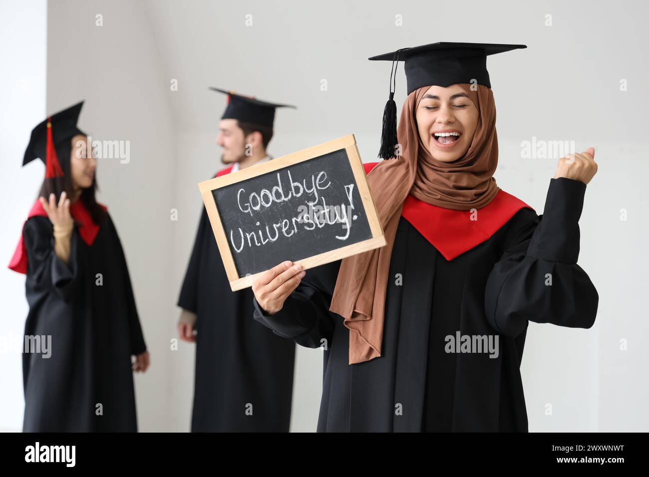Muslim female graduate student holding chalkboard with text GOODBYE ...
