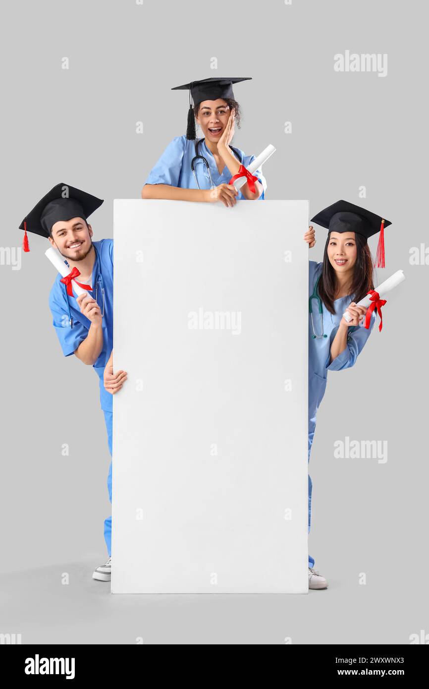 Medical graduate students with blank poster and diplomas on white ...