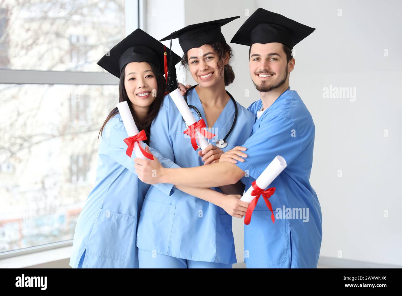 Medical graduate students with diplomas hugging in light room Stock Photo - Alamy