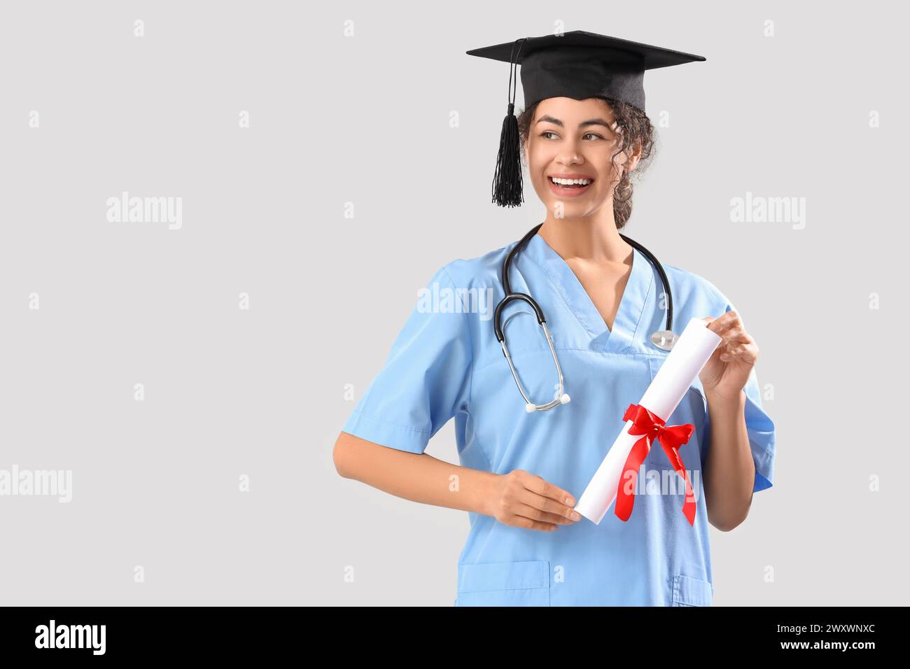 African-American female medical graduate student holding diploma on ...