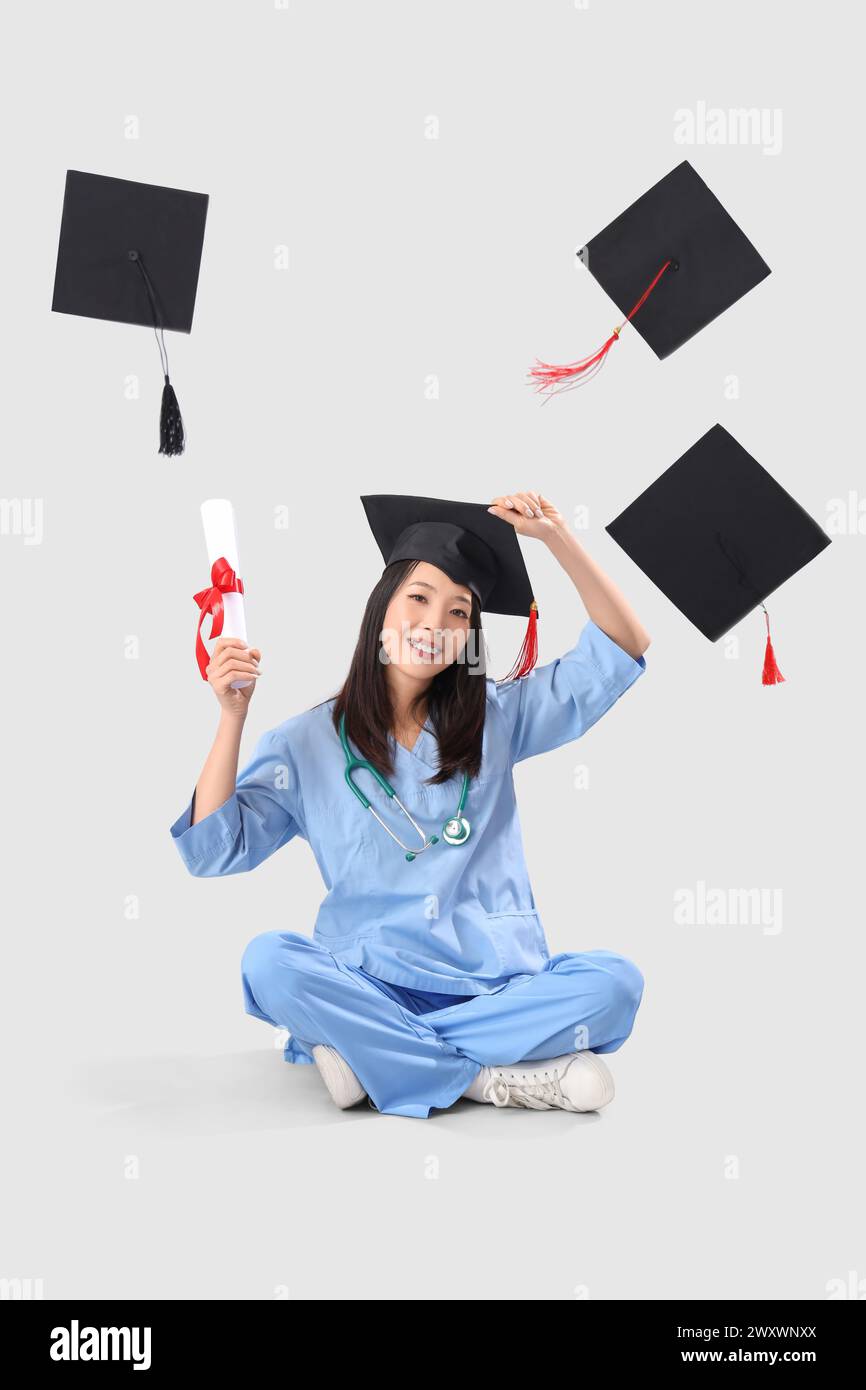 Asian female medical graduate student with diploma and falling mortar ...