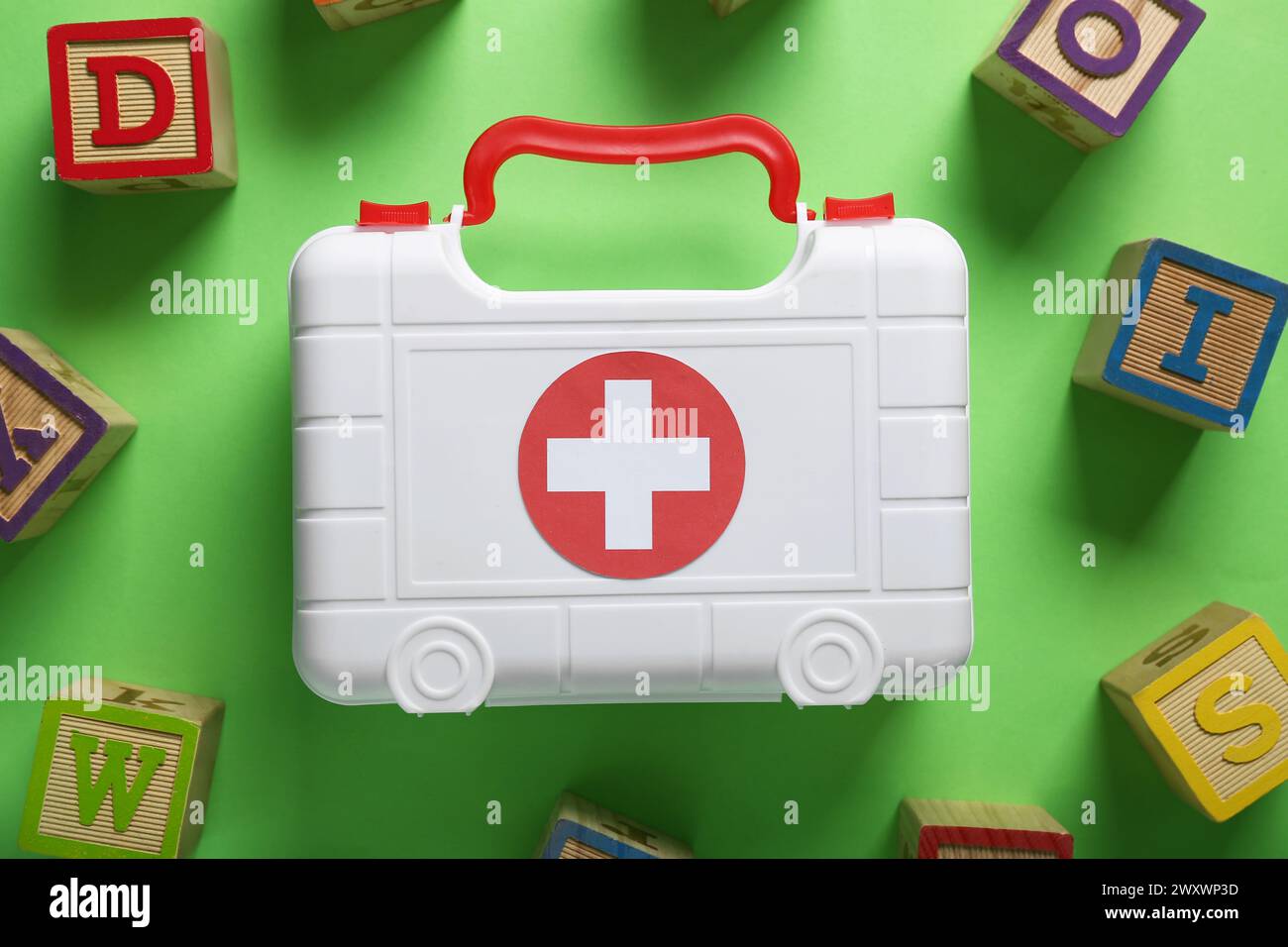 Toy first aid kit with children's alphabet blocks on green background ...