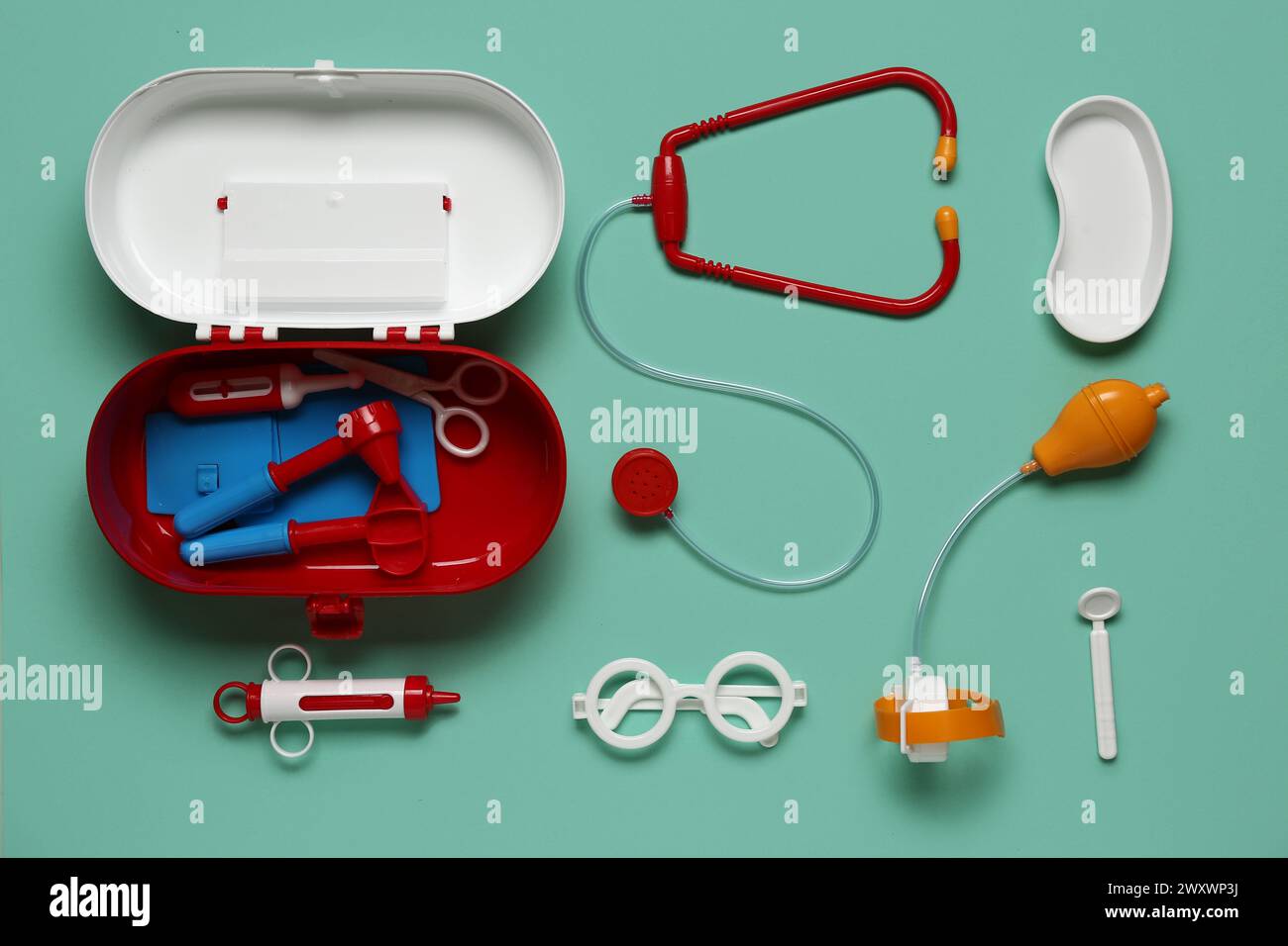 Toy first aid kit with stethoscope, injection and glasses on turquoise ...