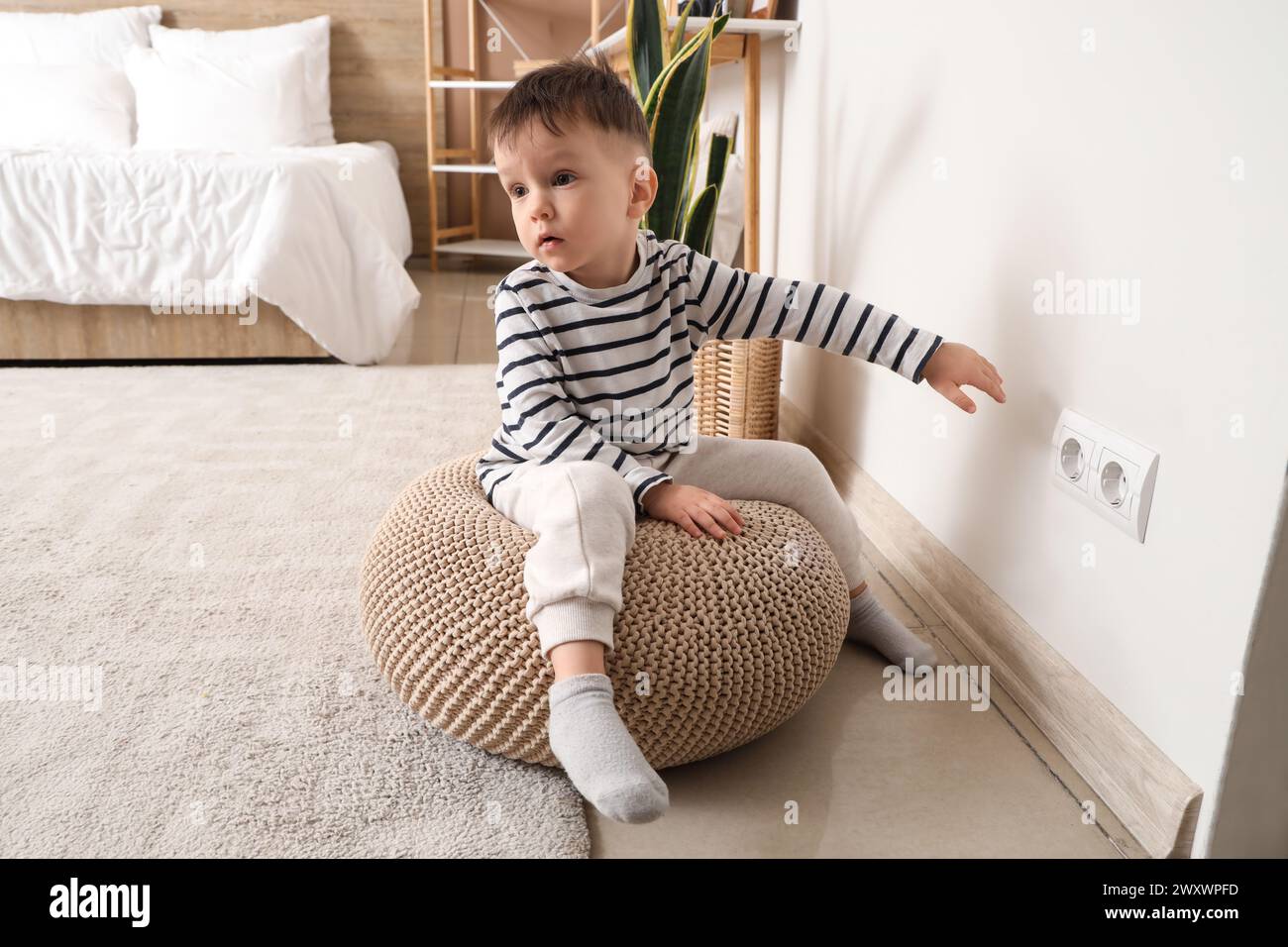 Little boy near electric socket in bedroom. Child at risk Stock Photo ...