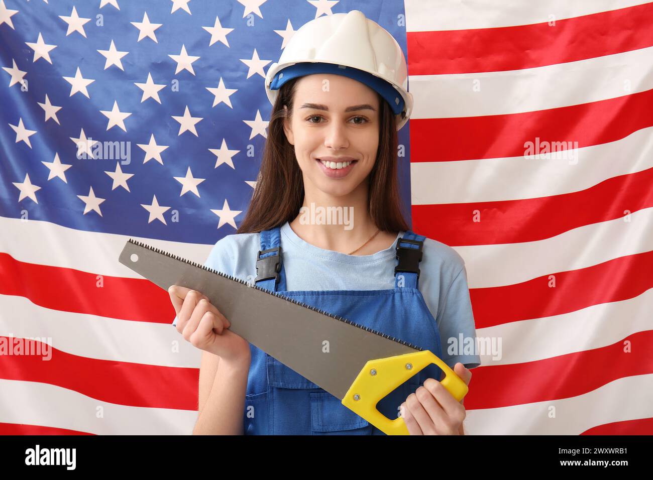 Female construction worker with hacksaw against USA flag background ...