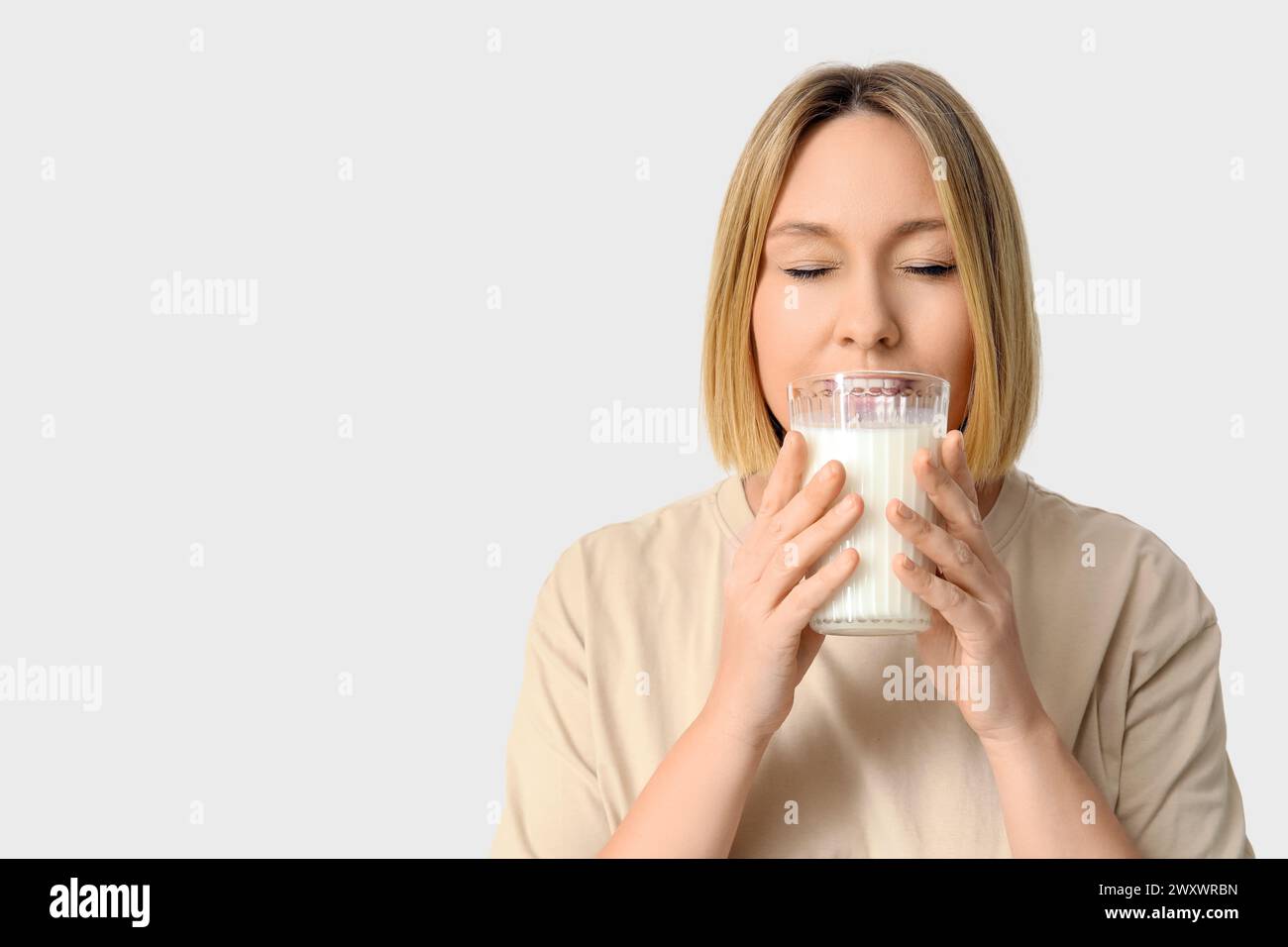Beautiful young woman drinking fresh milk on white background Stock ...