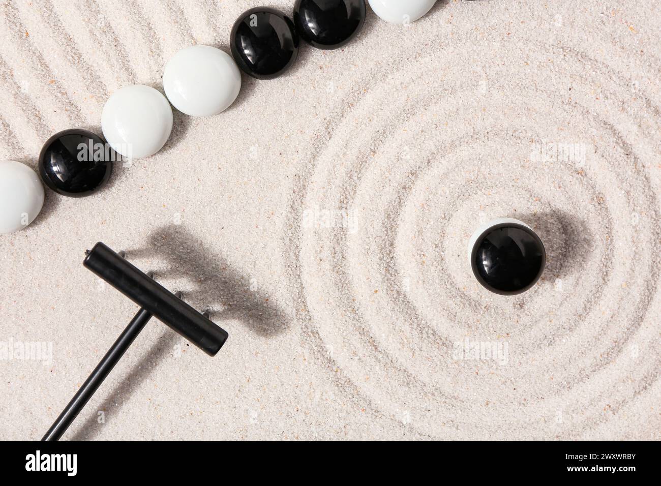 Rake and stones on sand with lines in Japanese rock garden, top view ...