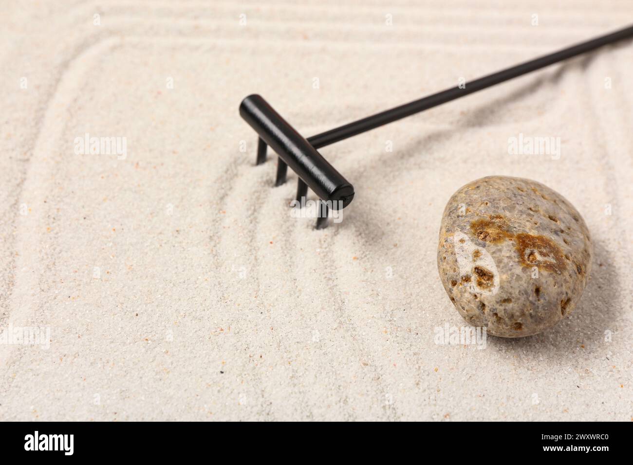 Rake and stone on sand with lines in Japanese rock garden. Zen concept ...