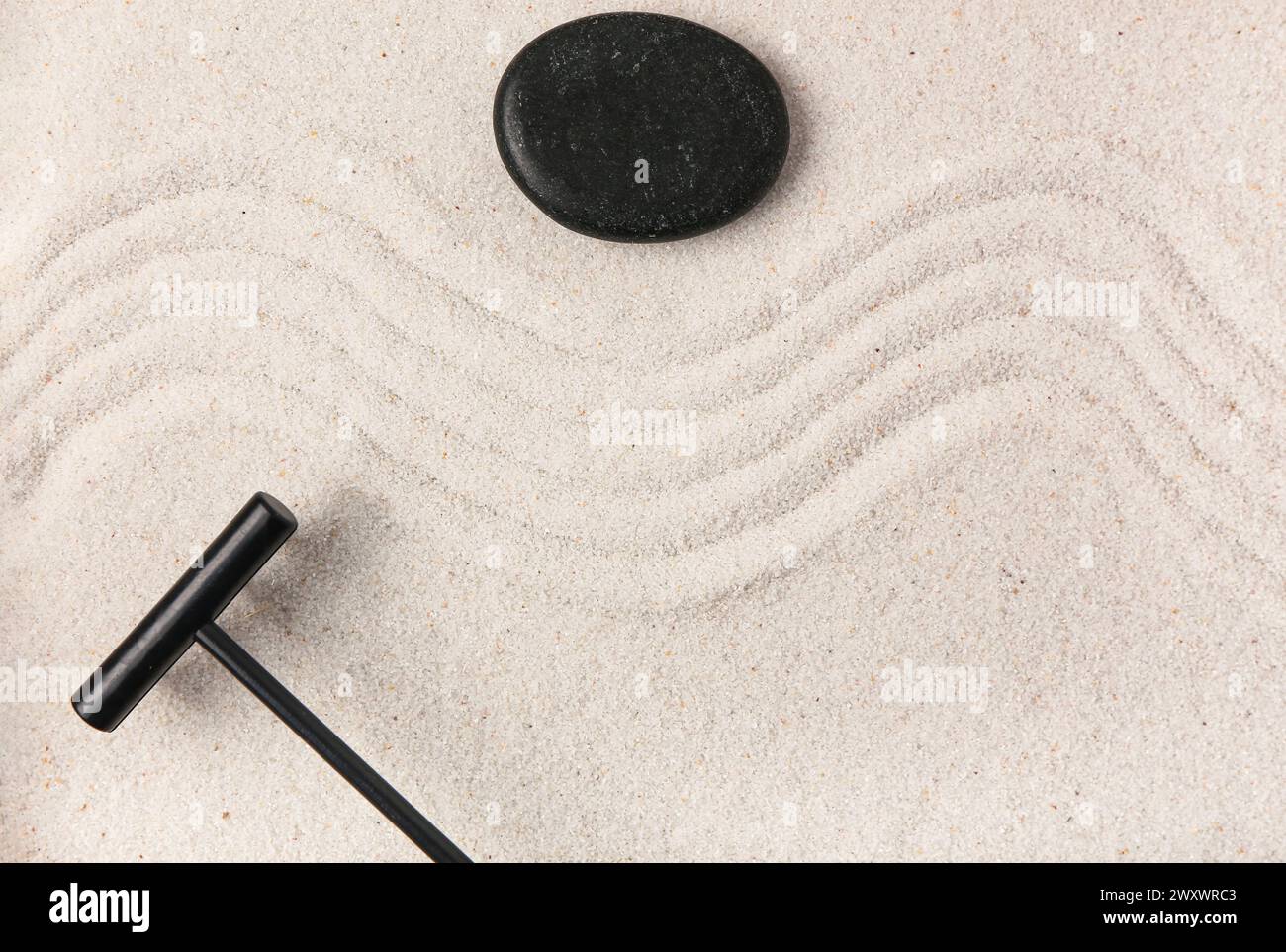 Rake and stone on sand with lines in Japanese rock garden. Zen concept ...