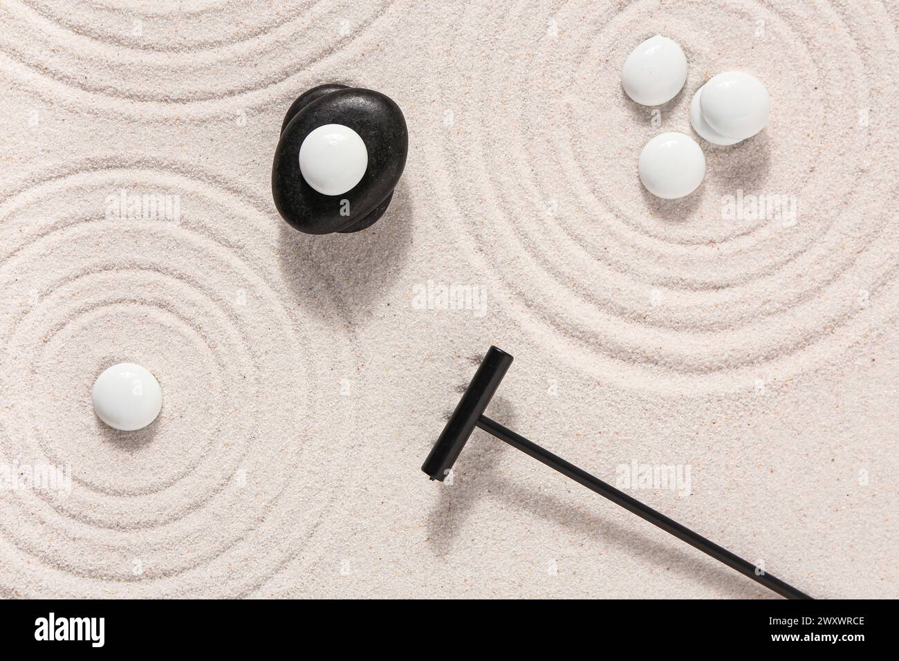 Rake and stones on sand with lines in Japanese rock garden, top view ...