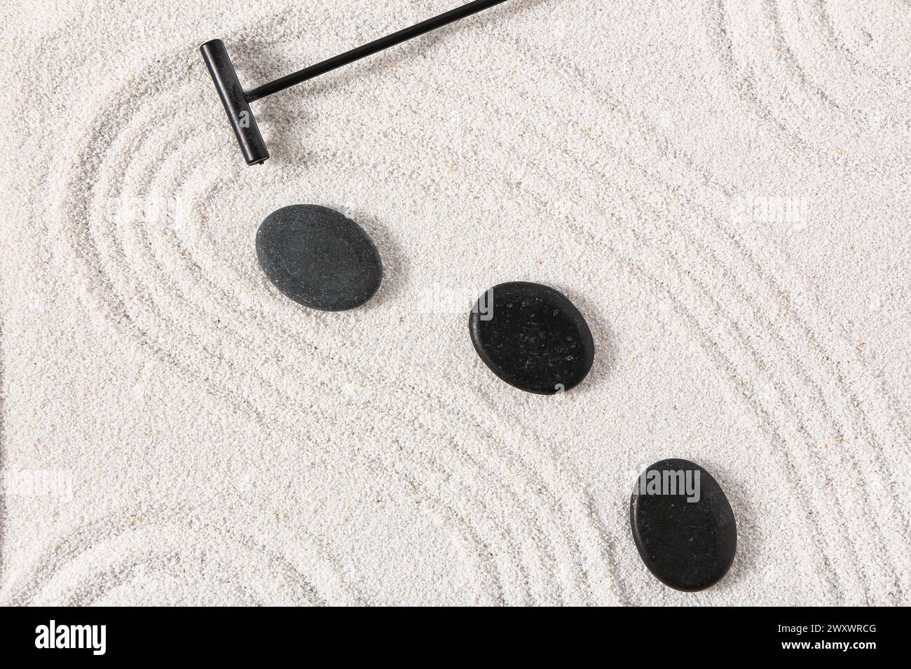 Rake and stones on sand with lines in Japanese rock garden. Zen concept ...