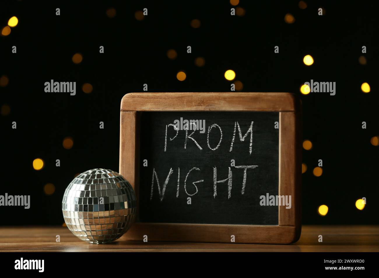Chalkboard with text PROM NIGHT and disco ball on wooden table against ...